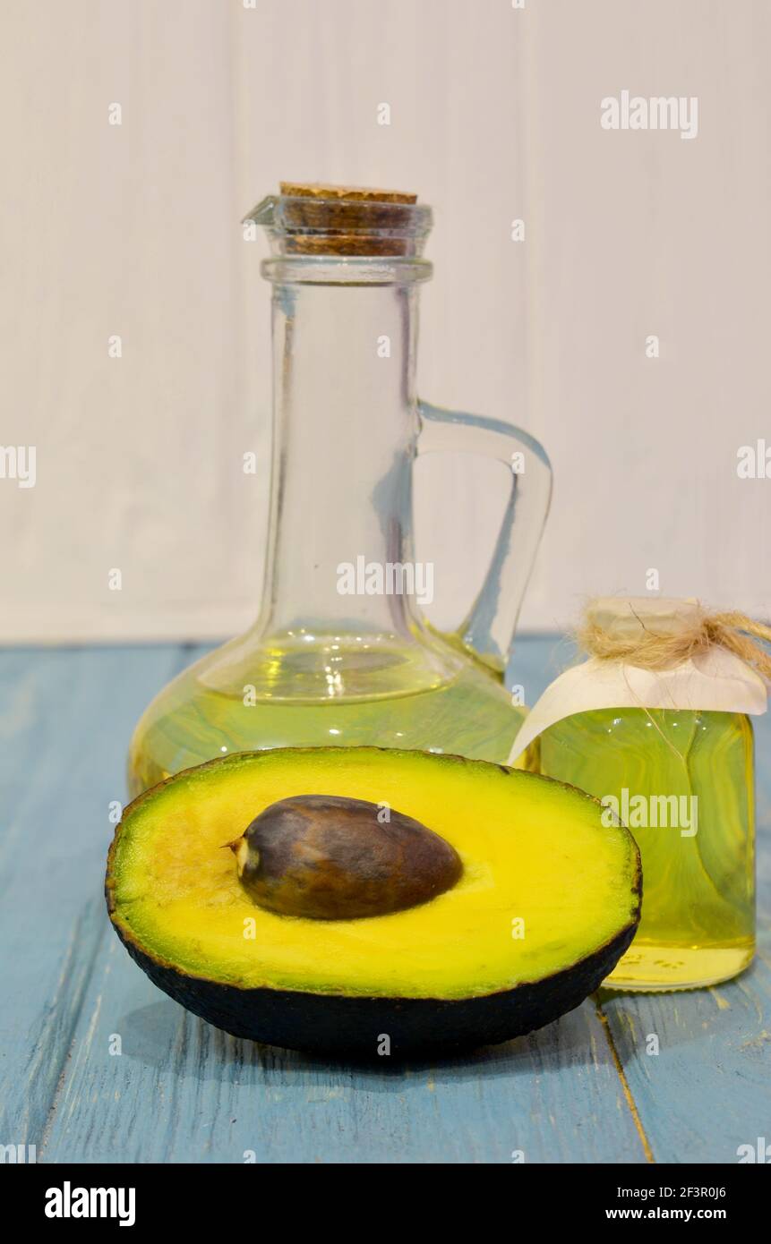 Avocado oil and cut in half avocado on blue wooden background Stock ...