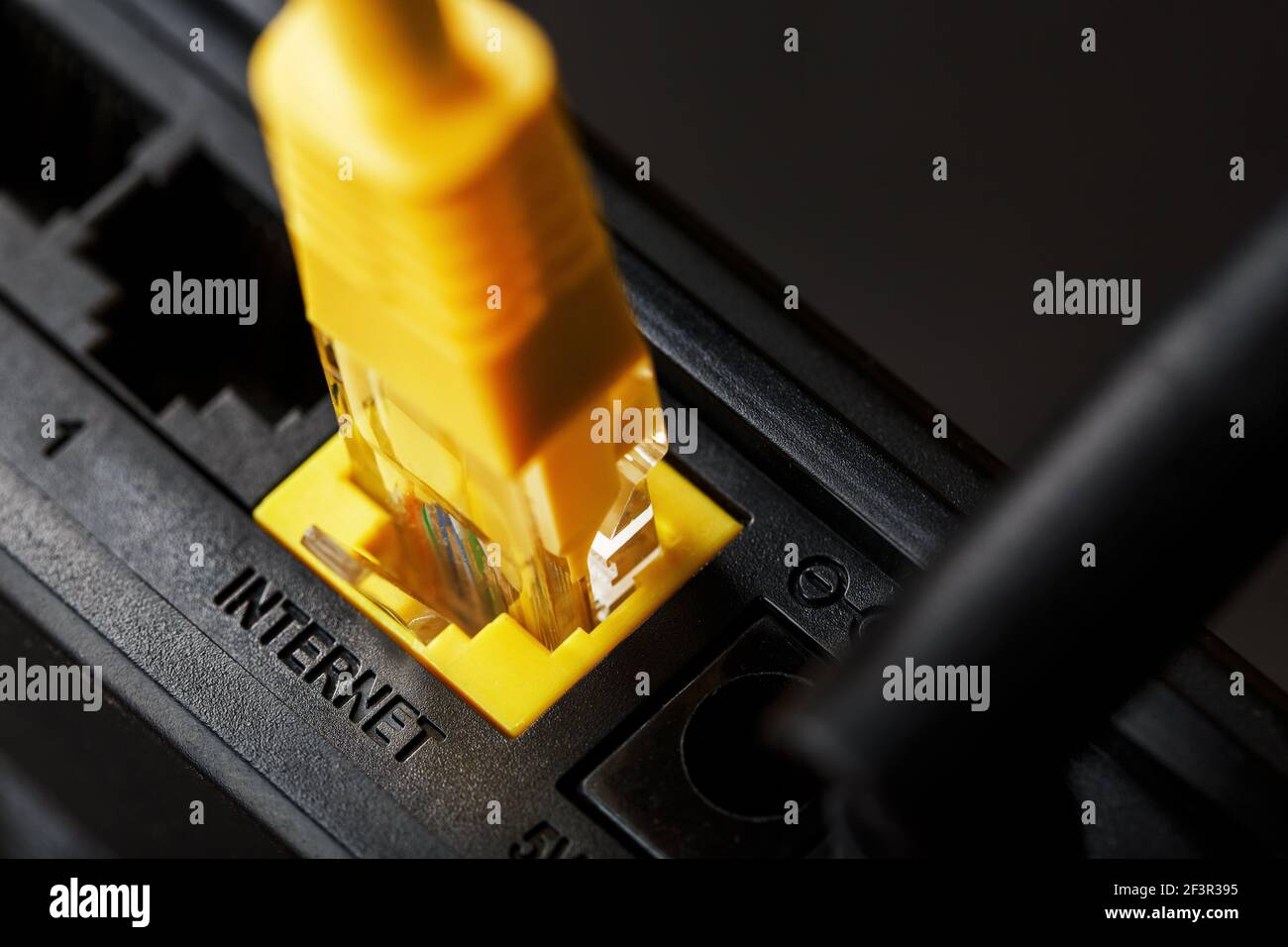 A yellow patch cord is inserted into the Wi-Fi port of the router to ...