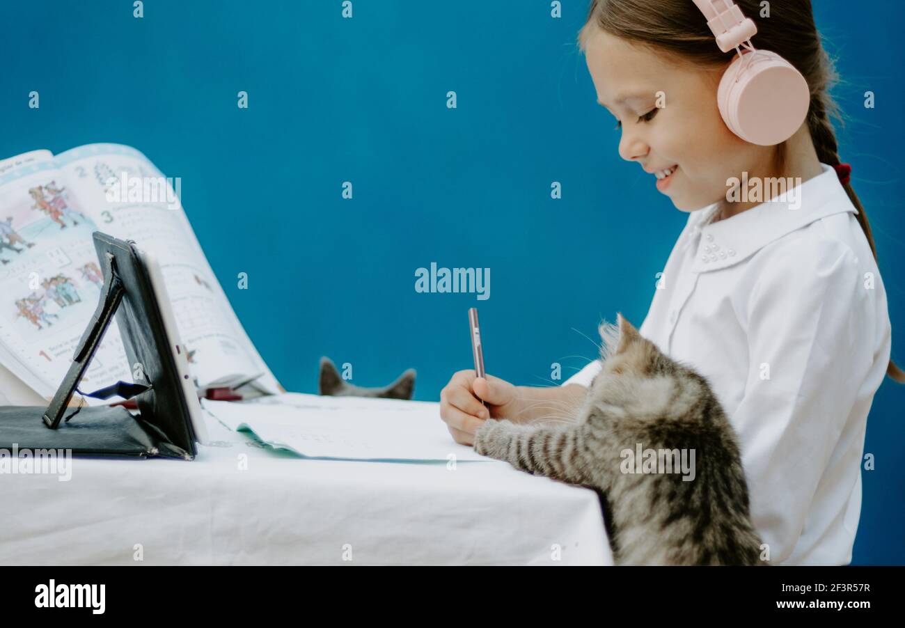 Young girl smiling doing online learning at home with book and tablet ...