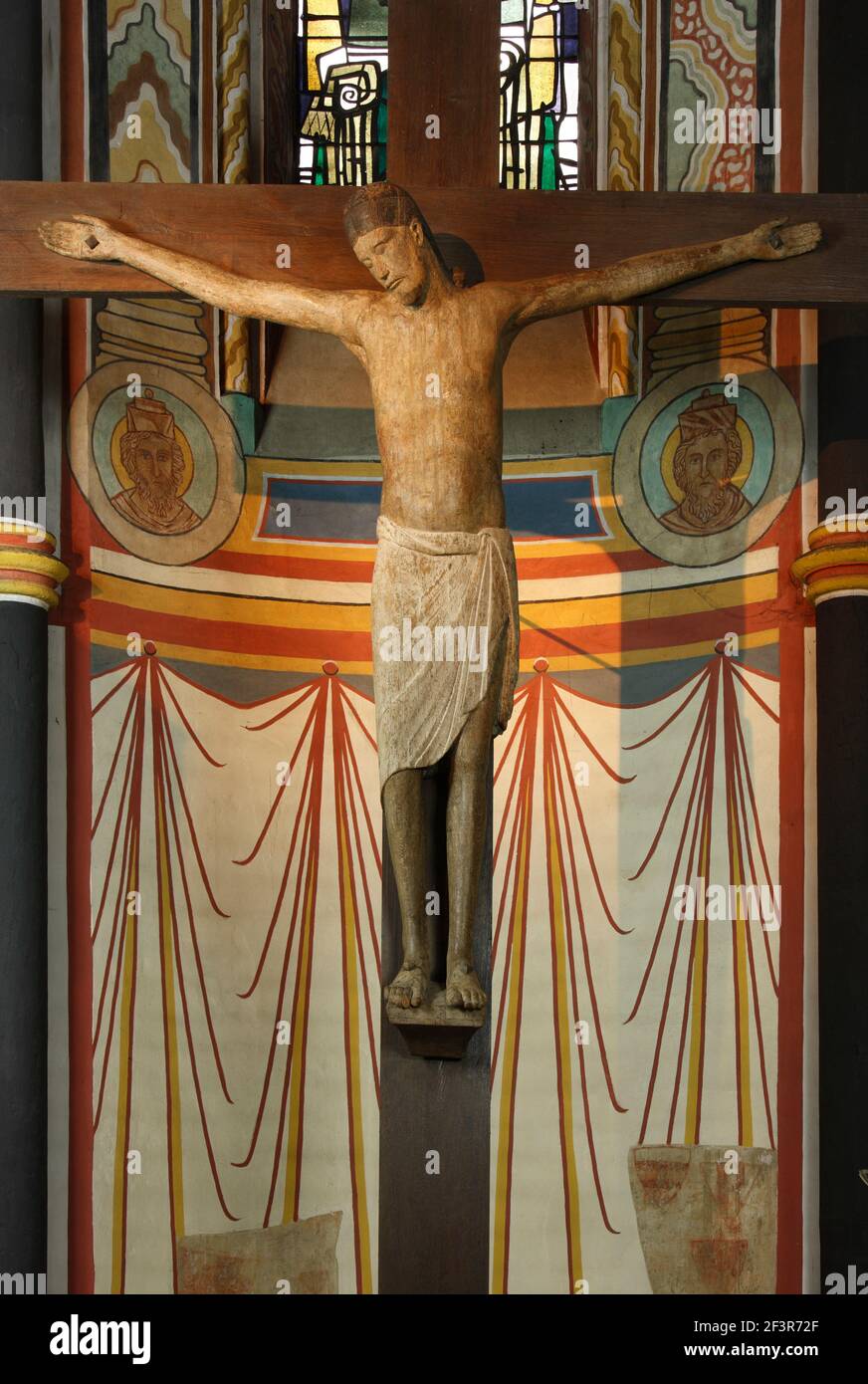 Romanesque style crucifix in front of colourful wall in choir in ...