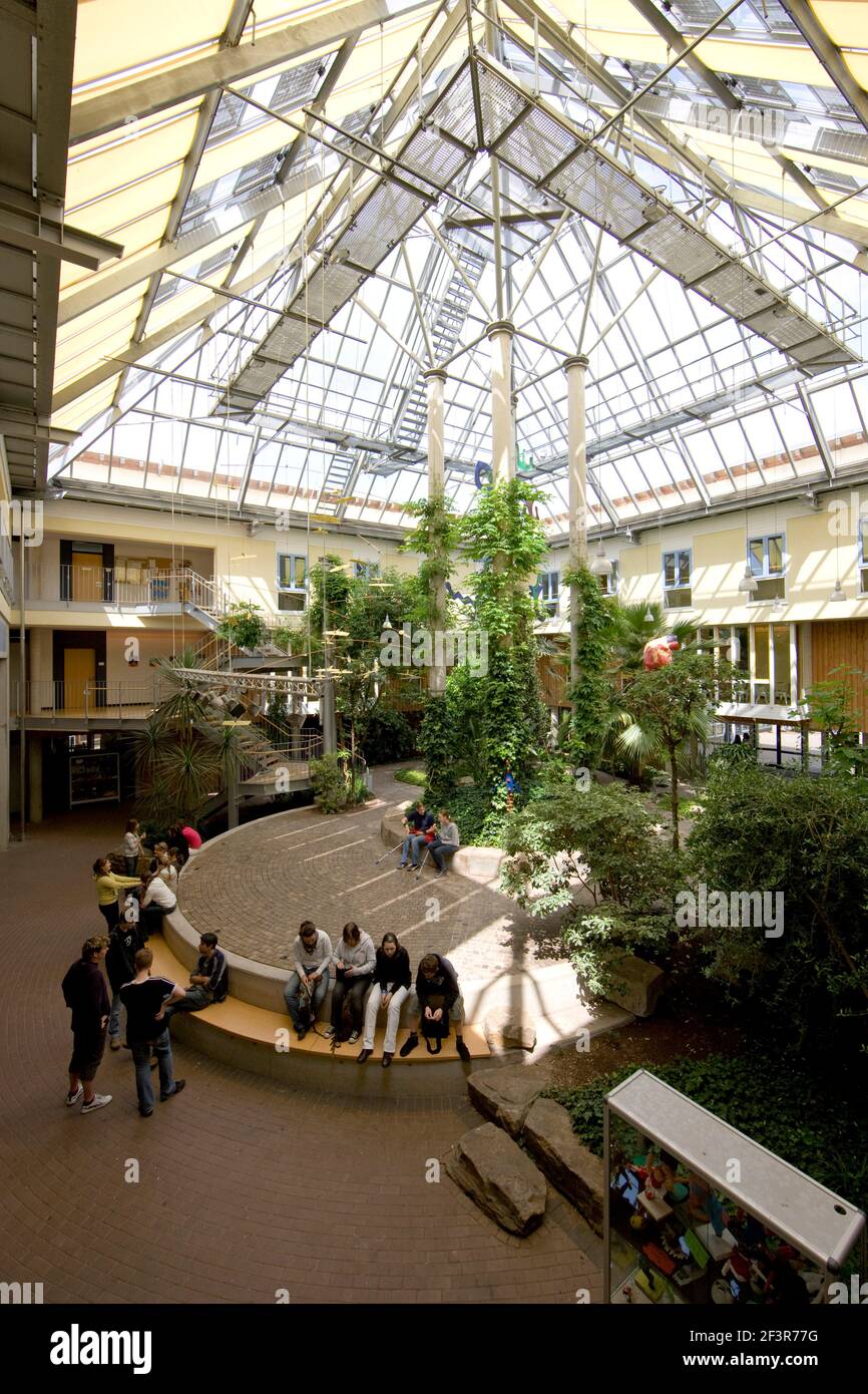 Students sit in an enclosed courtyard of comprehensive school with ...
