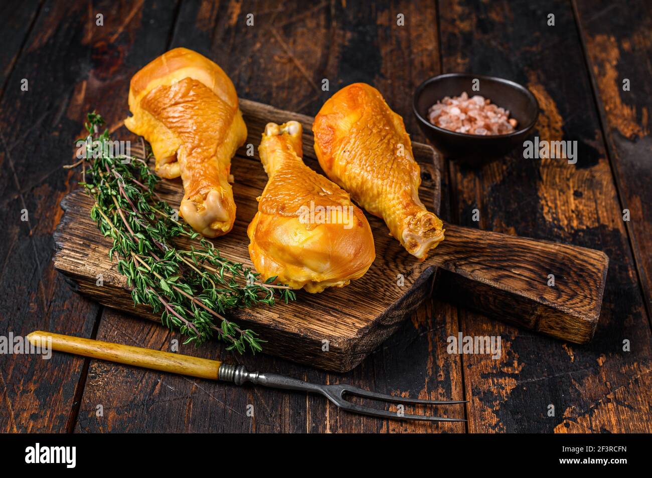 Marinated and Smoked chicken legs drumsticks on a wooden cutting board ...