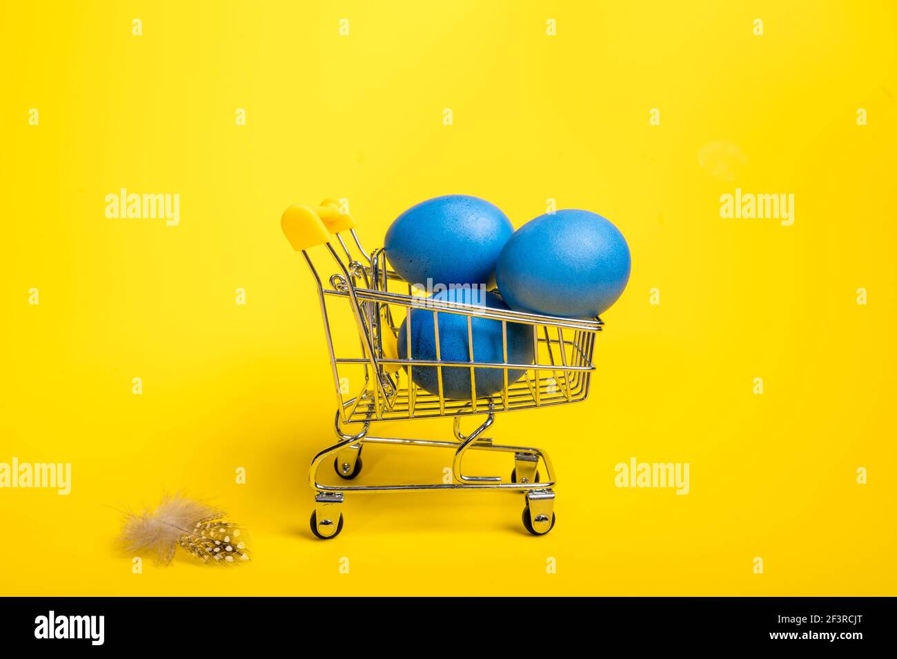Shopping trolley with blue easter eggs and feather. Copy space Stock ...