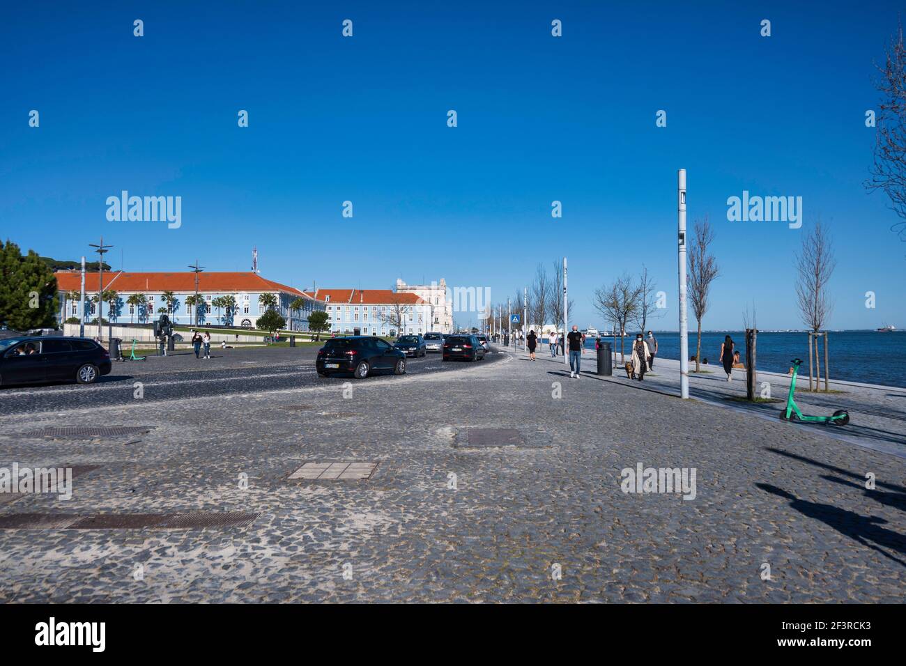People walking and cars driving along the Tagus riverfront promenade on ...
