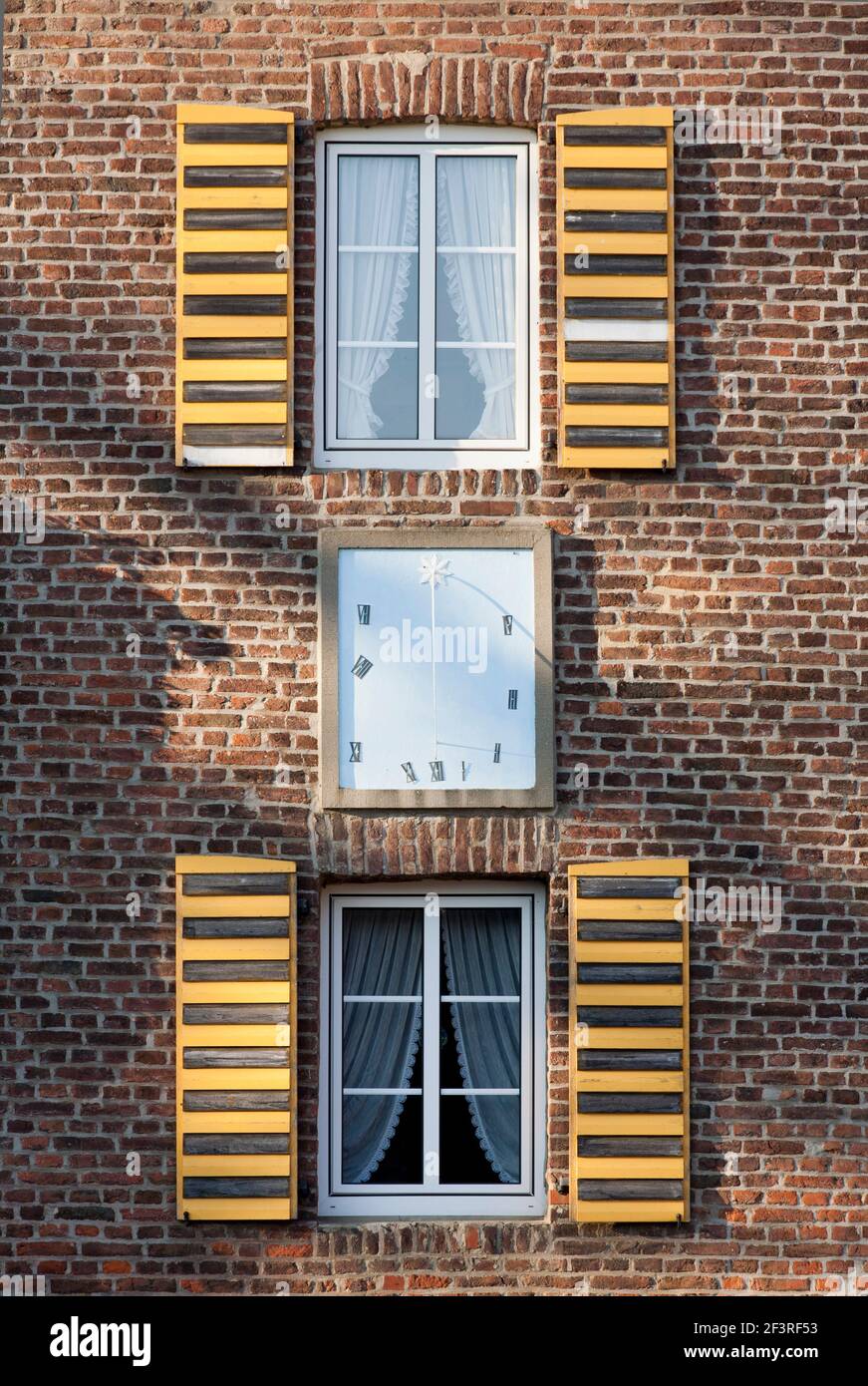Sundial between windows on brick facade of inner courtyard, 1920's ...