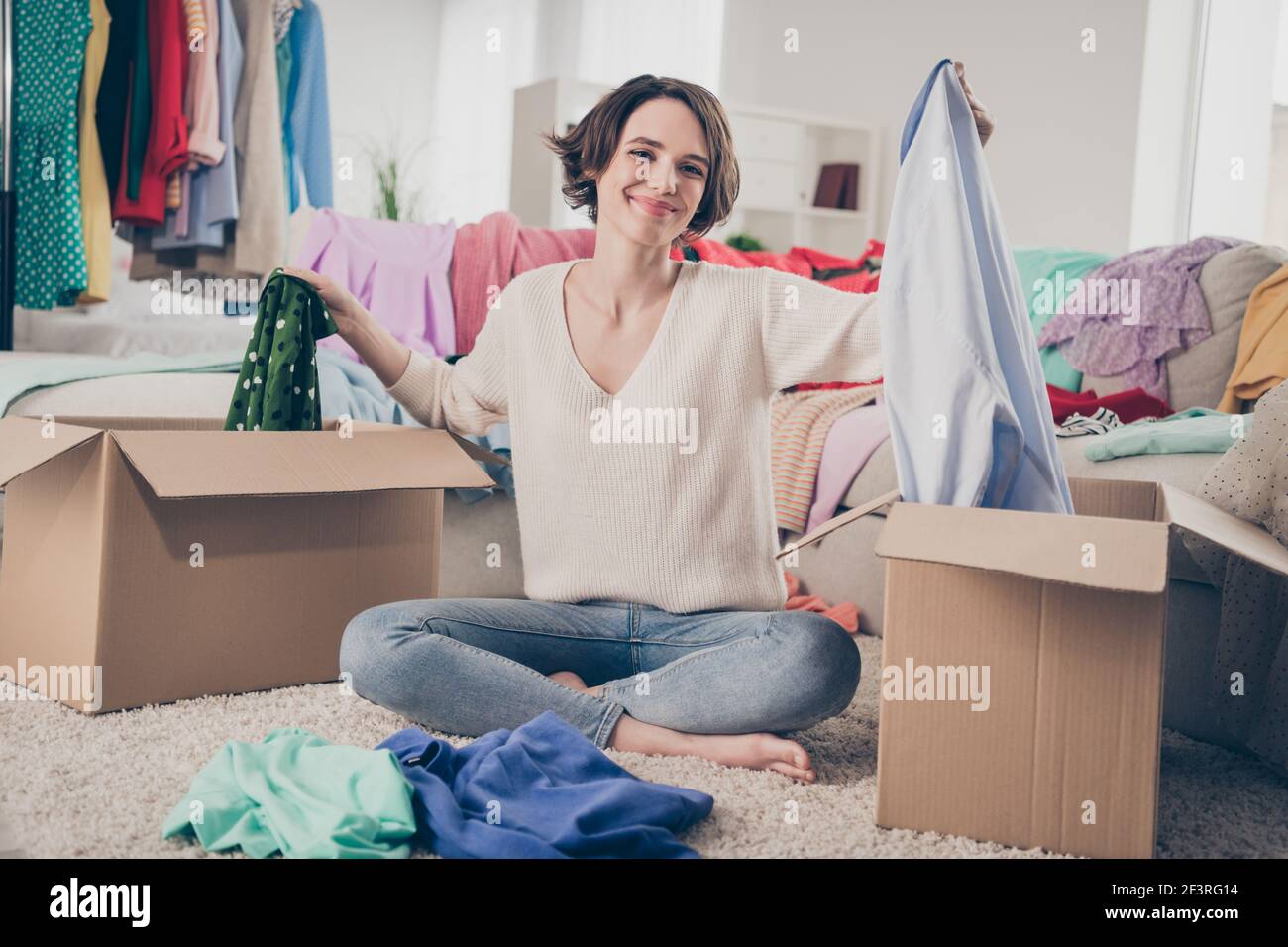 Full body photo of charming positive lady sit on carpet hands hold ...