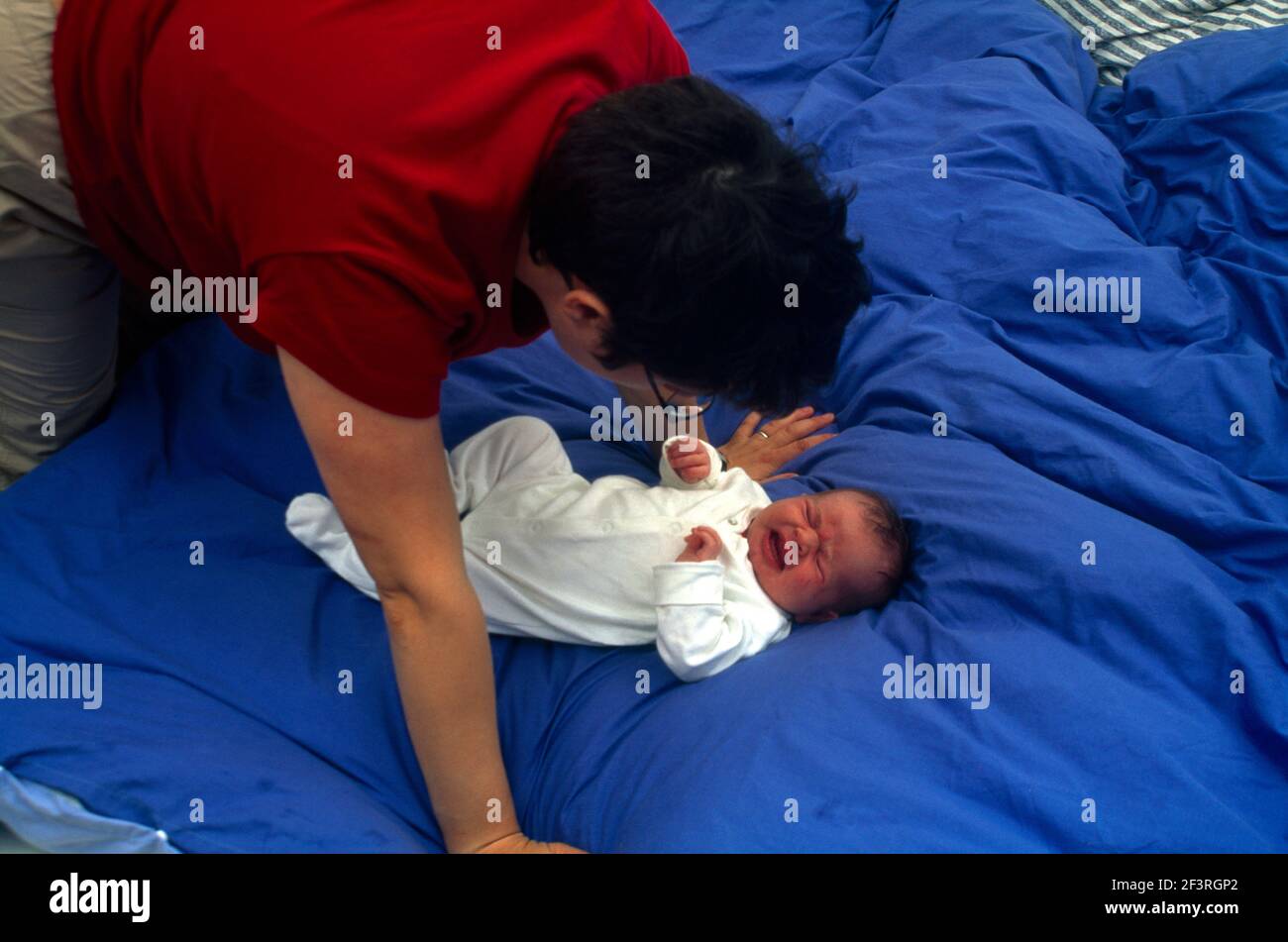 Mother with Baby Crying on Bed England Stock Photo - Alamy
