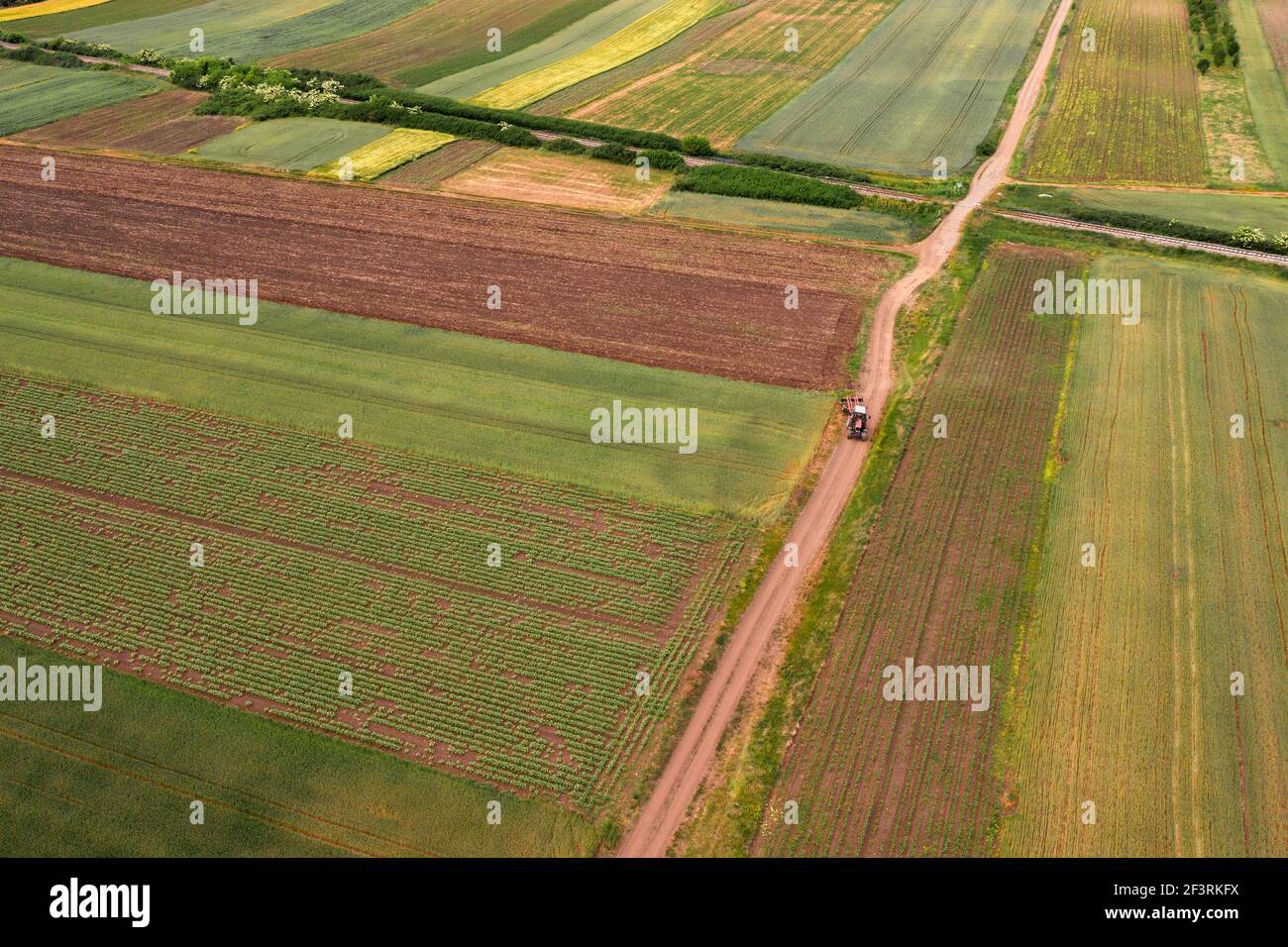 Aerial view of agricultural tractor on dirt road driving through ...