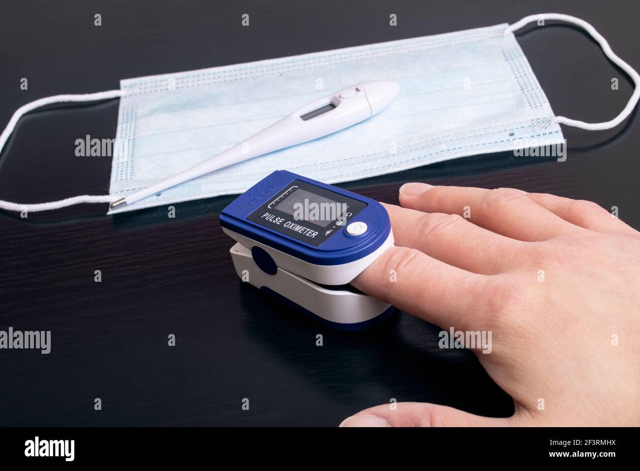 Mask, stethoscope, thermometer and oximeter on black background close ...