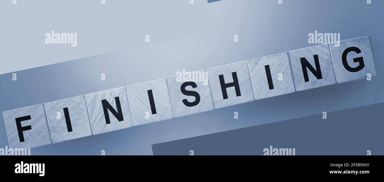 Finishing message word on a wooden cube blocks with blue background ...