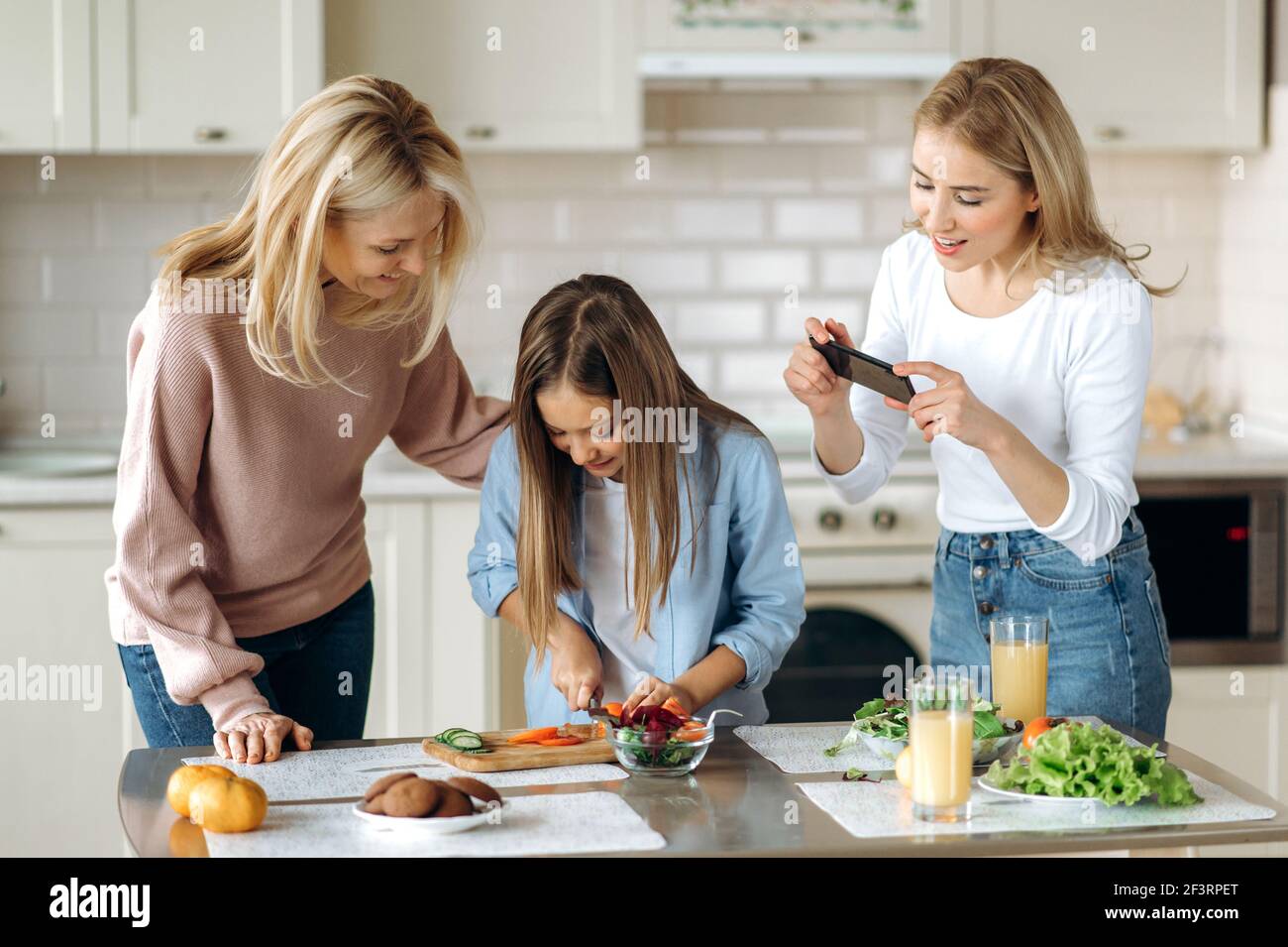 Three female generation at the kitchen. Mom and grandma teach a small ...