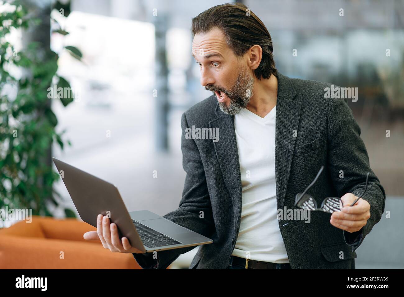 Stylish handsome caucasian adult man with laptop. A bearded confident ...