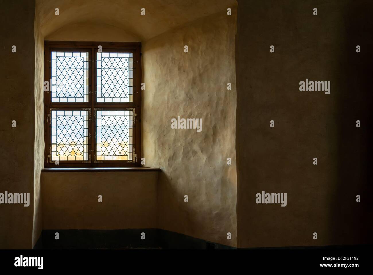 Dim light going through stained-glass window in thick wall niche in the ...