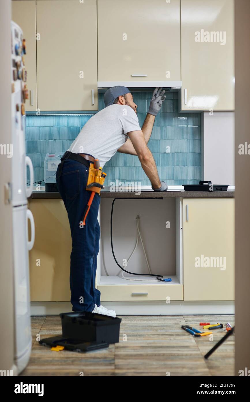 Fix anything. Full length shot of young handyman examining a kitchen ...