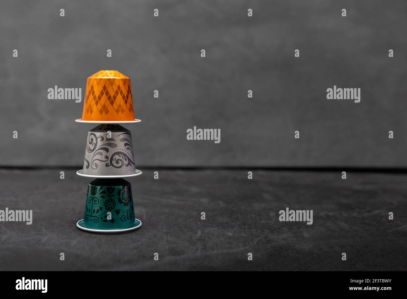 Three coffee capsules stacked on a dark grey background. Close-up. New ...