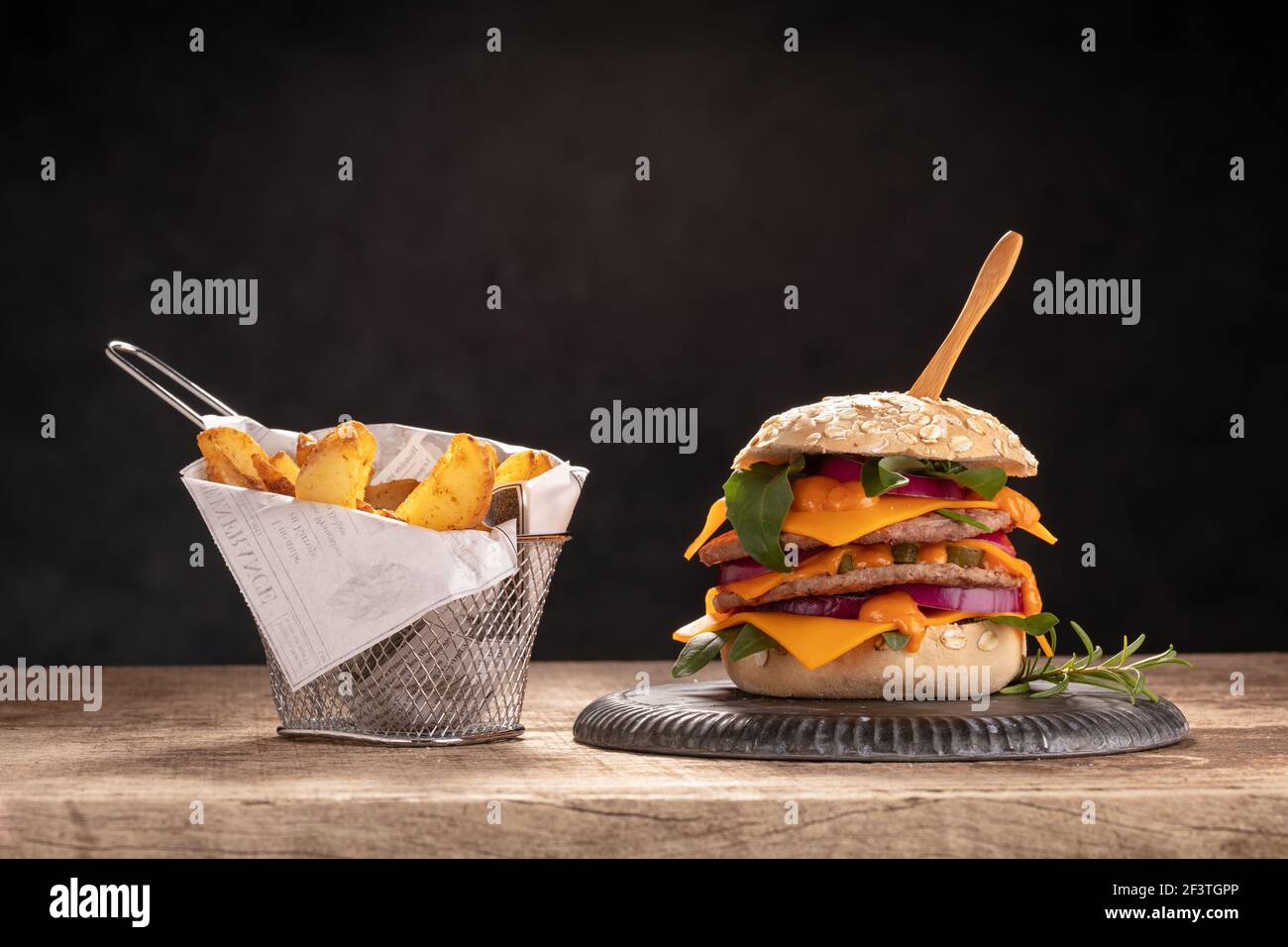 Cheeseburger with potatoes on a wooden table and a dark background ...