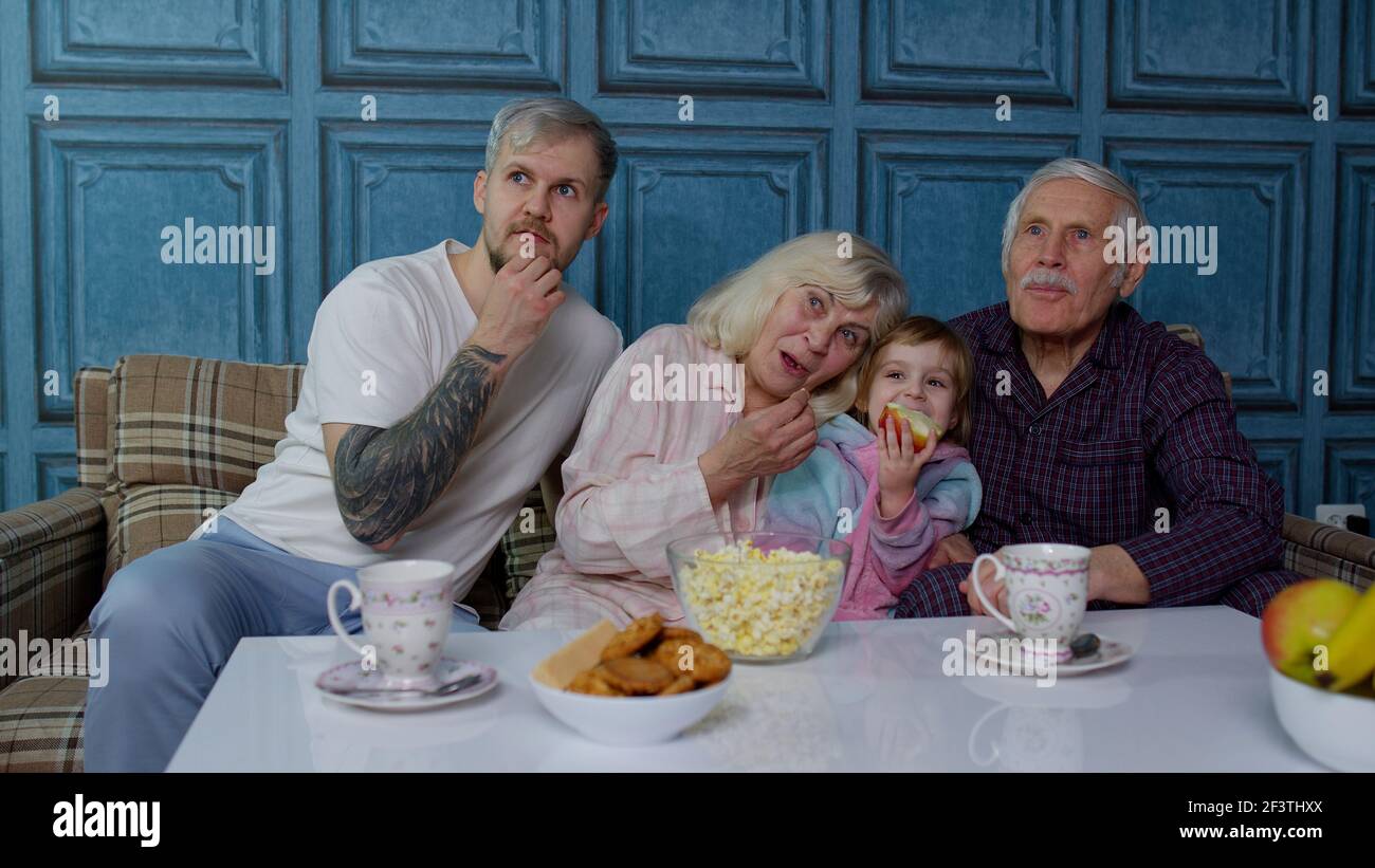 Multigenerational family watch TV with young girl kid at home, getting ...