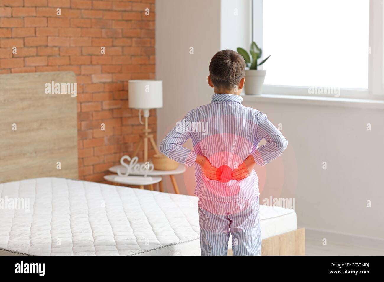 Little boy suffering from back pain in morning because of uncomfortable ...