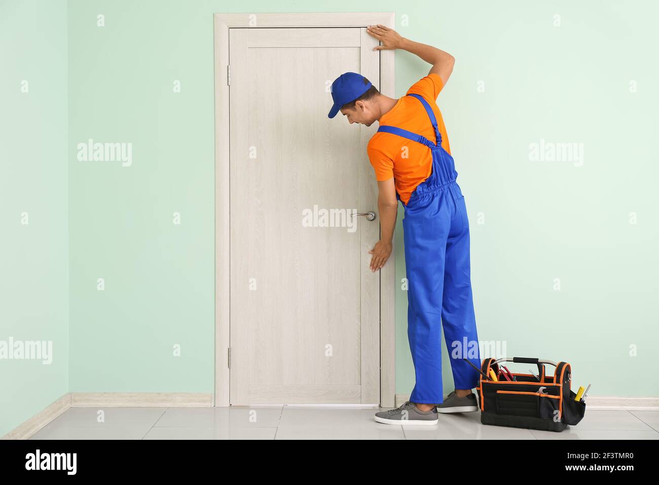 Construction worker repairing door indoors Stock Photo - Alamy