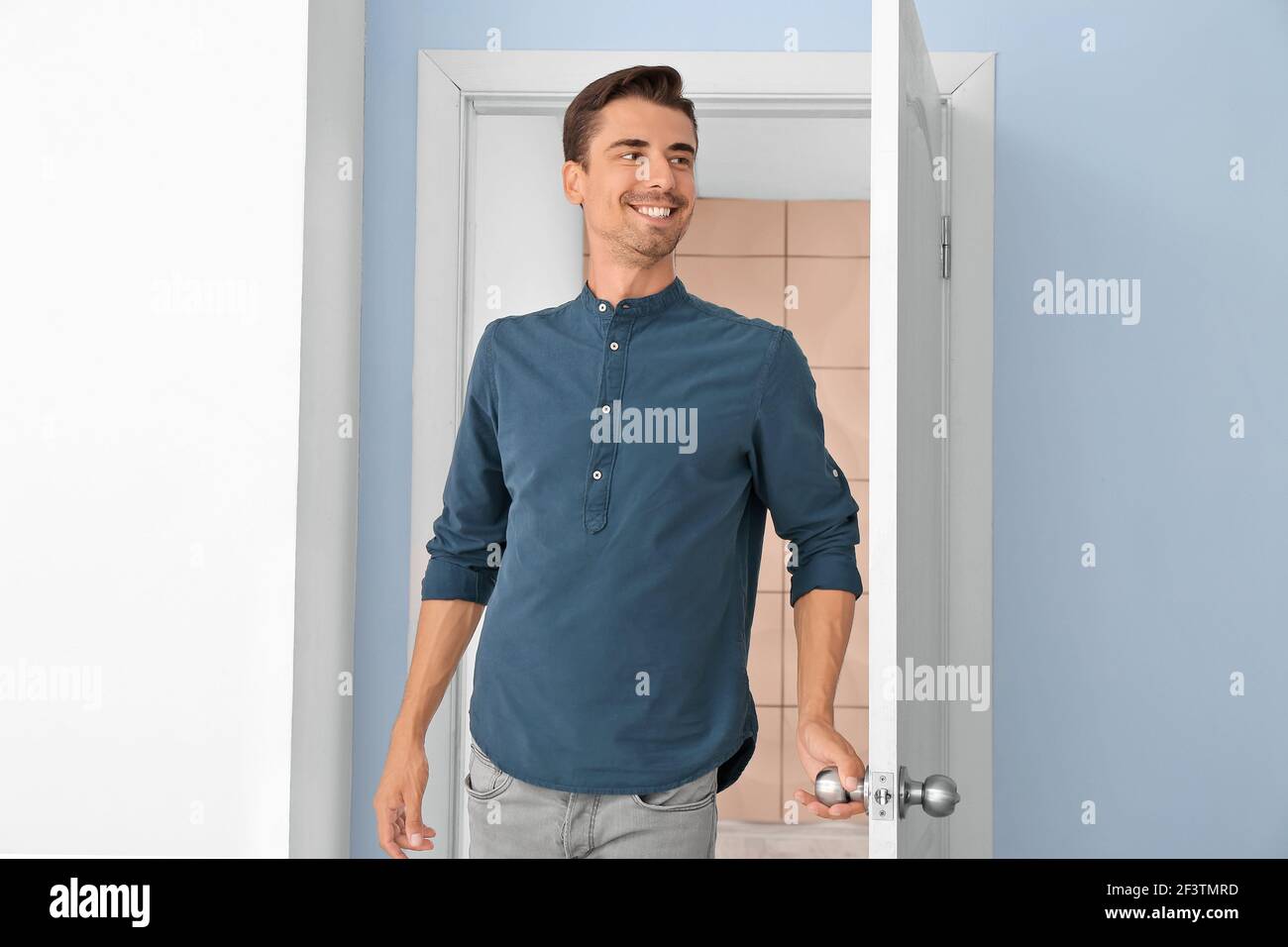 Happy man standing in doorway at home Stock Photo - Alamy