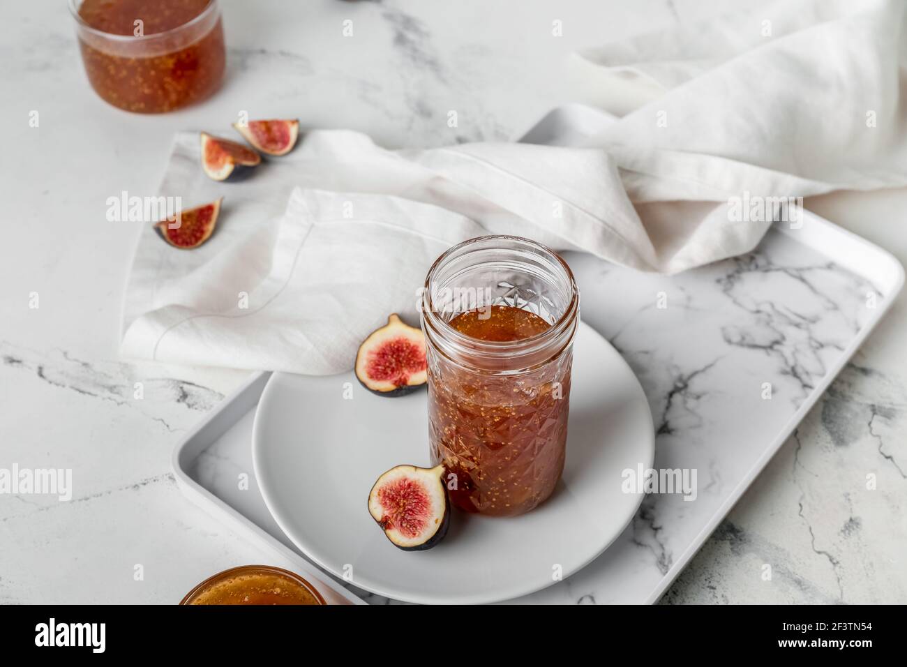 Jar of sweet fig jam on white table Stock Photo - Alamy