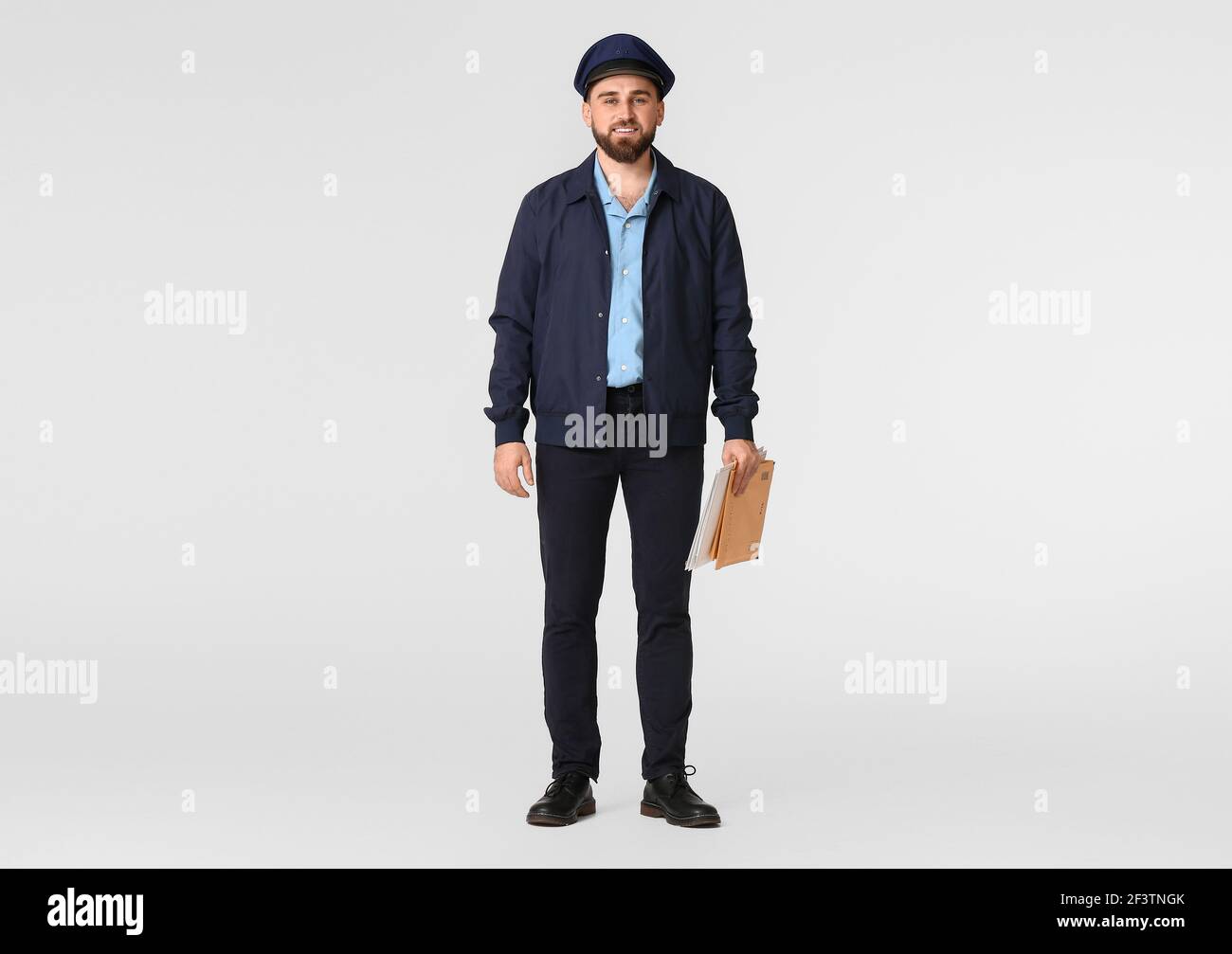 Handsome young postman on light background Stock Photo - Alamy
