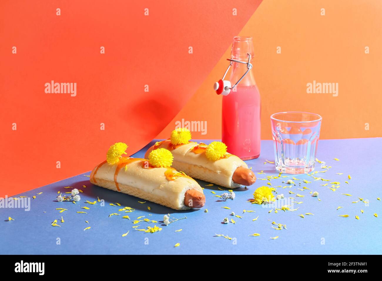 Tasty hot dogs with flowers on color background Stock Photo - Alamy