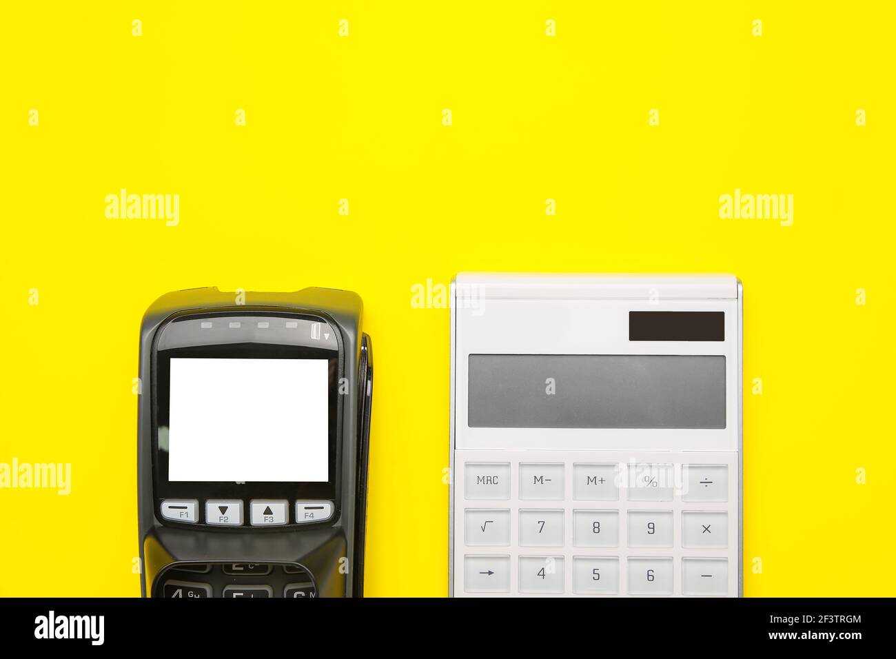 Calculator with payment terminal on color background Stock Photo - Alamy