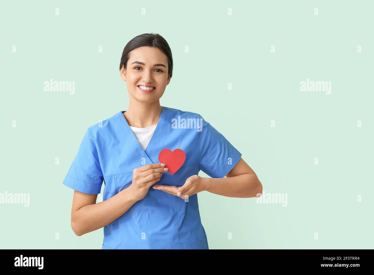 Cardiologist with red heart on color background Stock Photo - Alamy