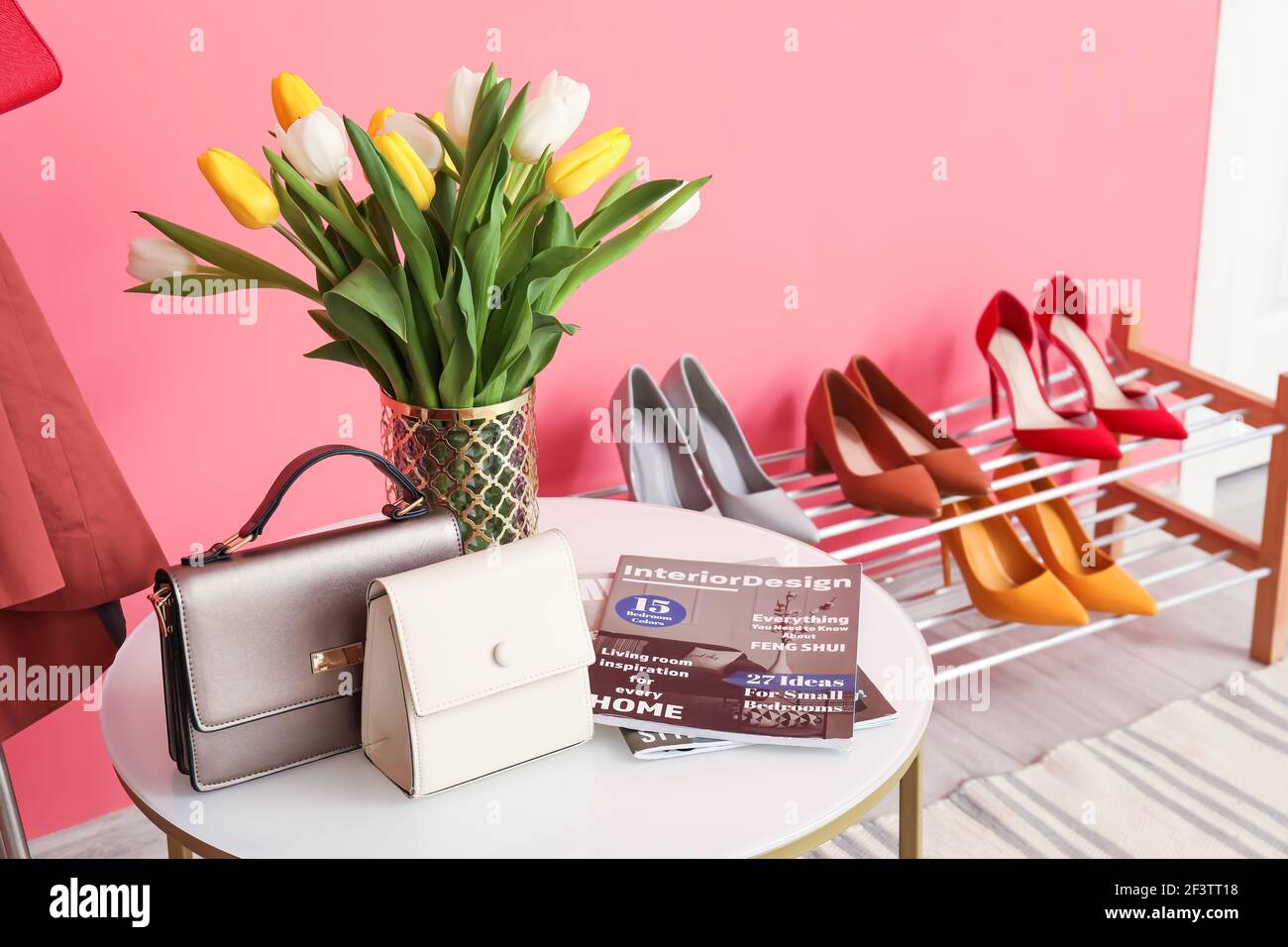 Bouquet of spring flowers and female bags on table in modern hallway ...