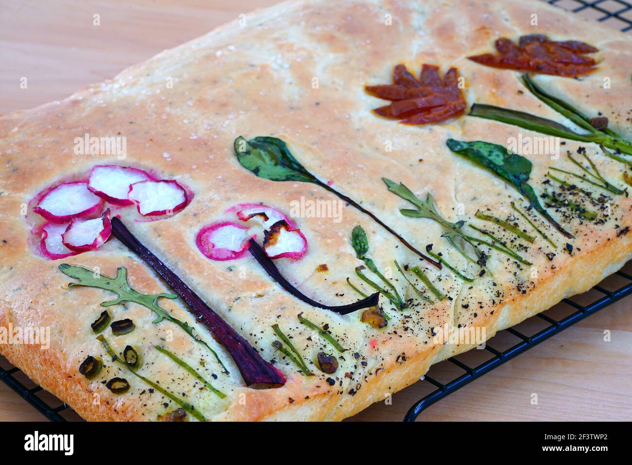 View of a focaccia bread decorated with a garden made of vegetables on ...