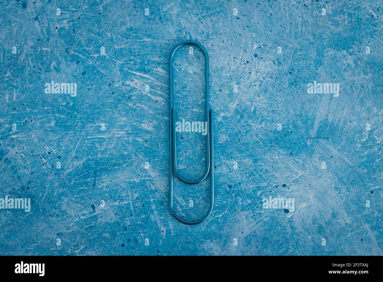 flatlay of blue paper clips on abstract blue texture with copy space ...