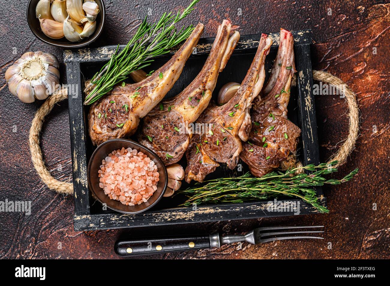 Grilled lamb chops steaks in a wooden tray. Dark background. Top view ...