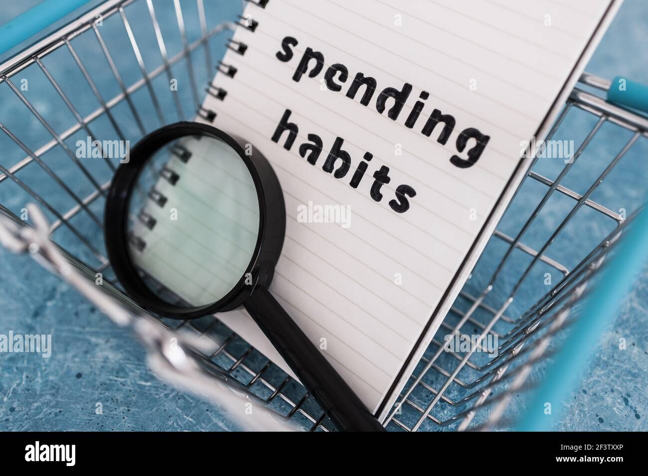 spending habits text on notepad with shopping basket and magnifying ...