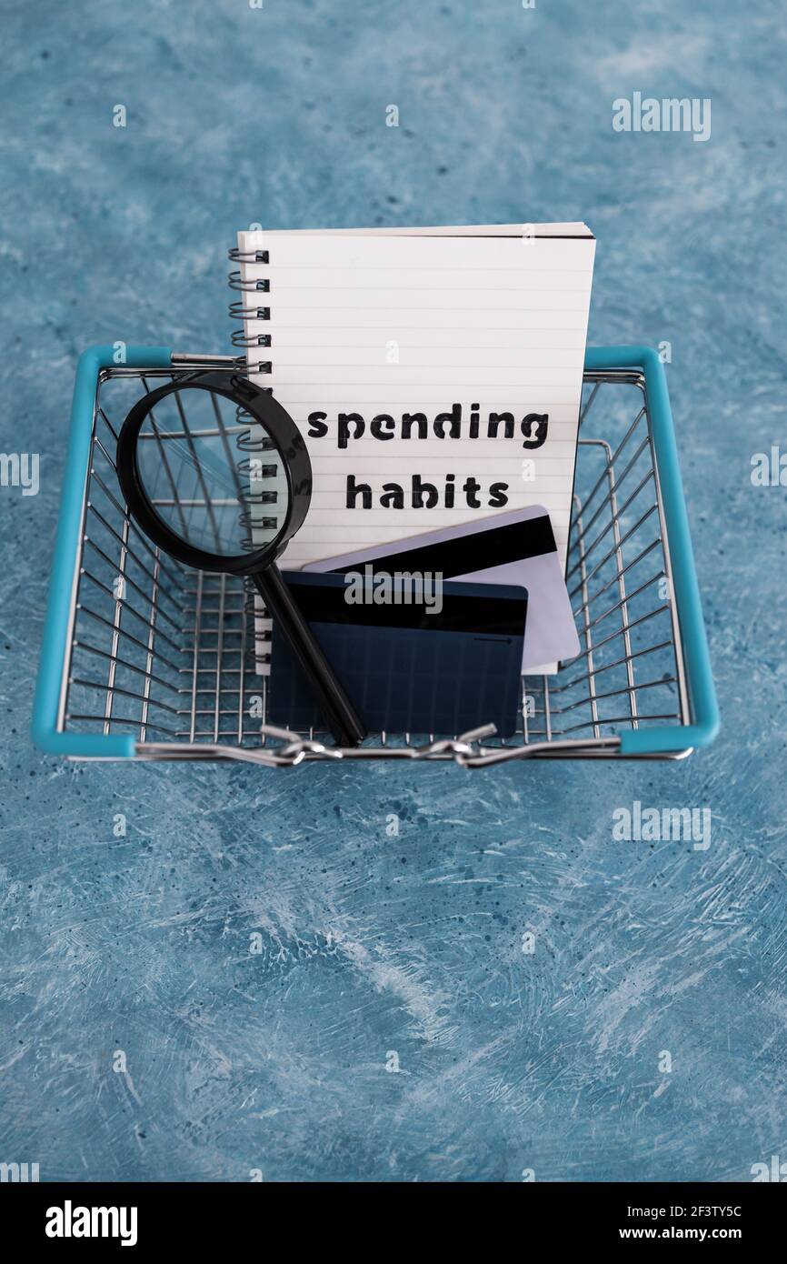 spending habits text on notepad with shopping basket and magnifying ...