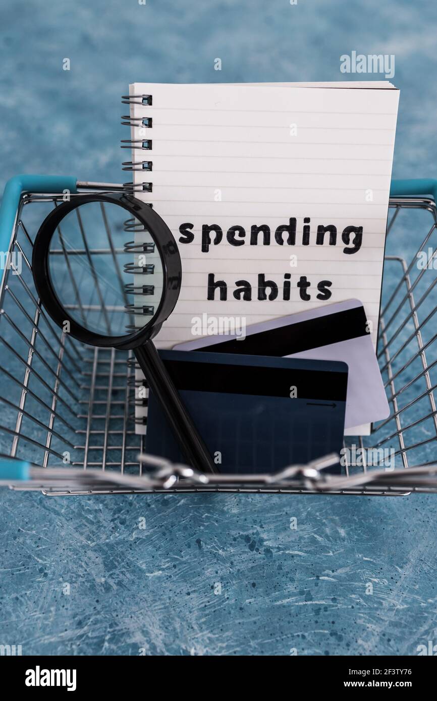 spending habits text on notepad with shopping basket and magnifying ...