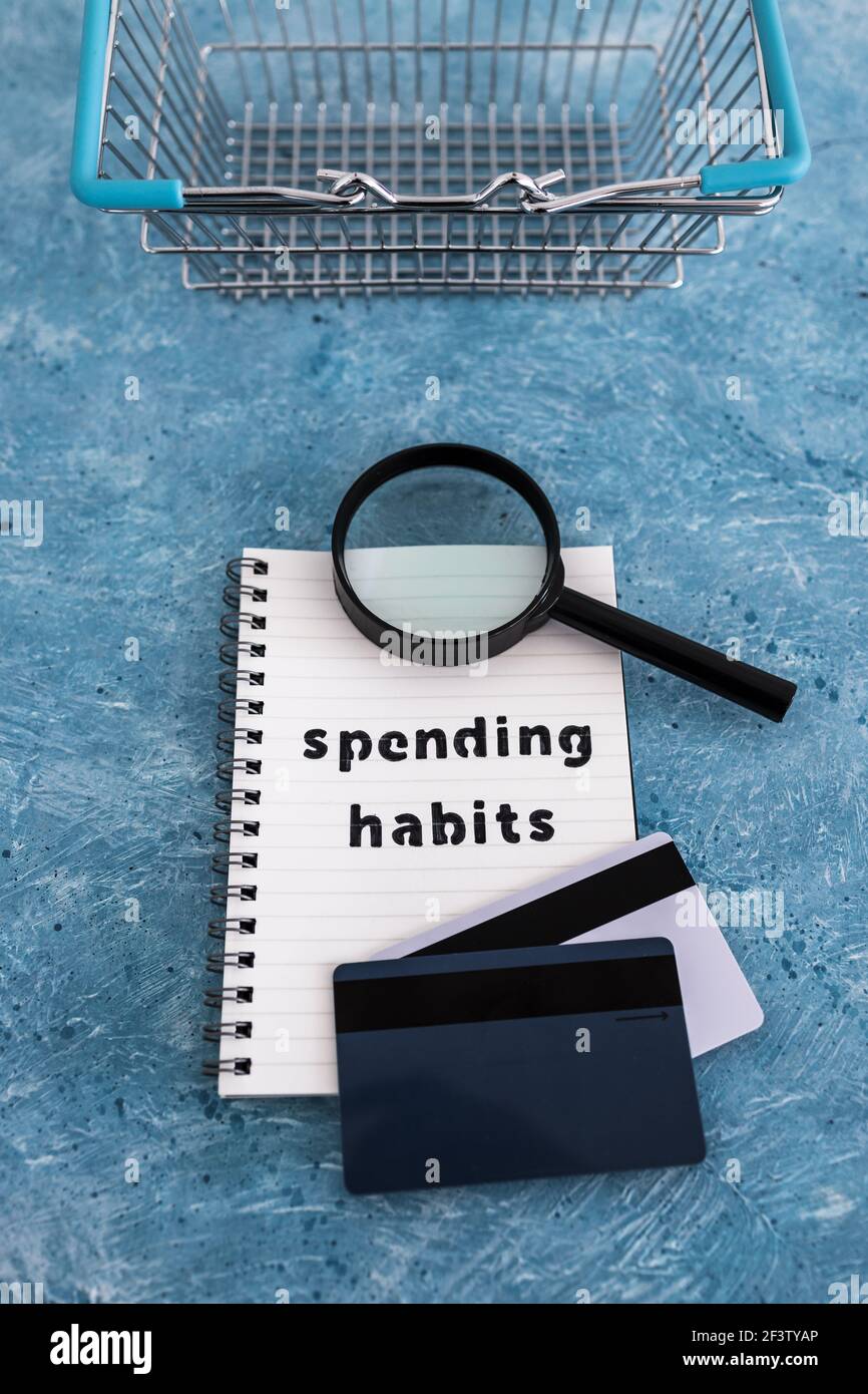 spending habits text on notepad with shopping basket and magnifying ...