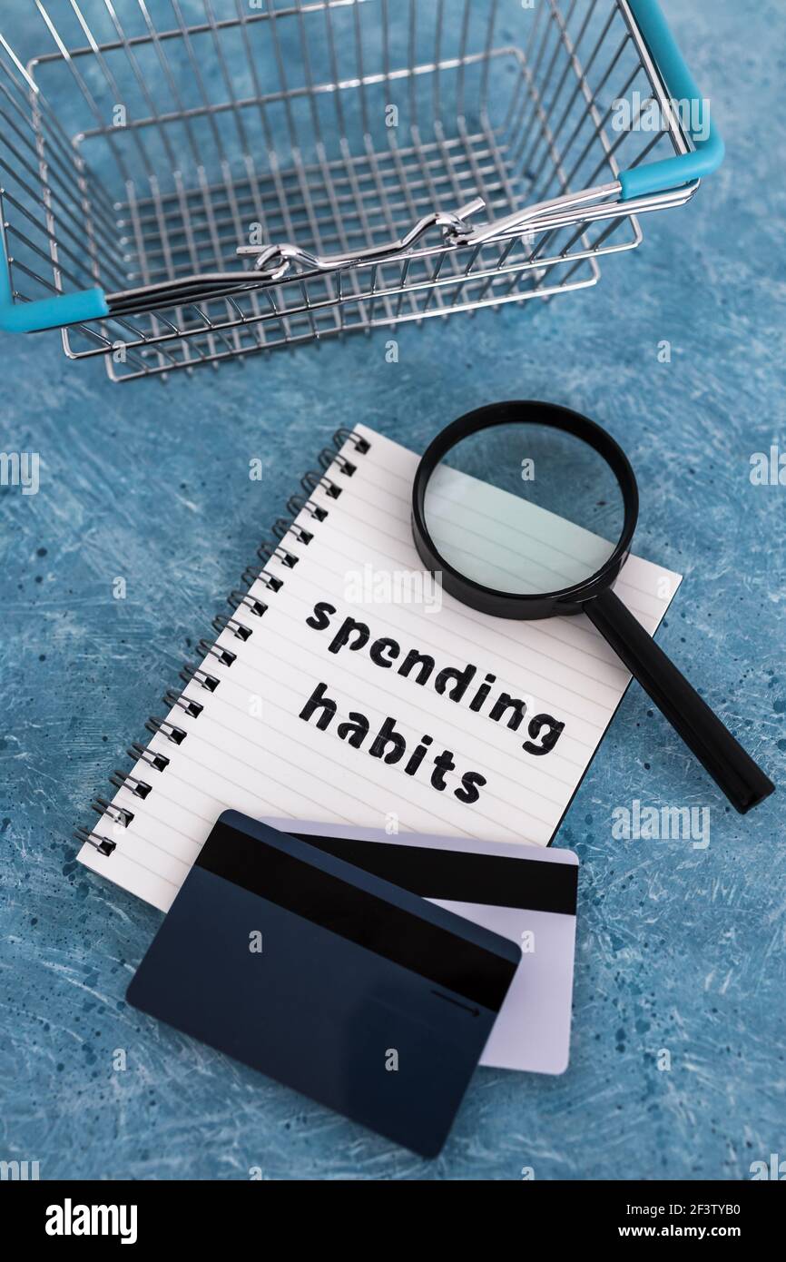 spending habits text on notepad with shopping basket and magnifying ...