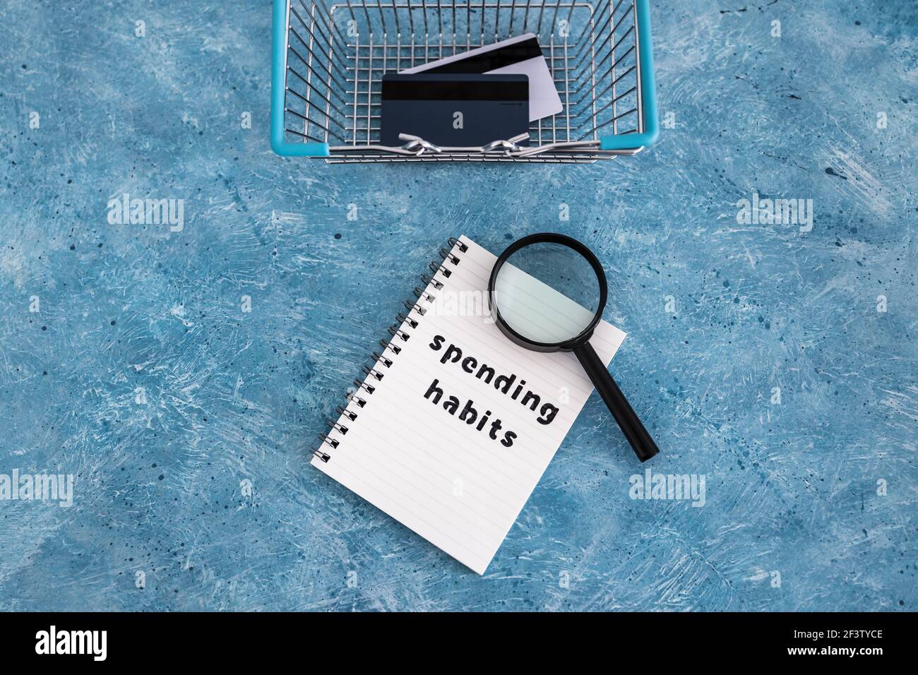 spending habits text on notepad with shopping basket and magnifying ...