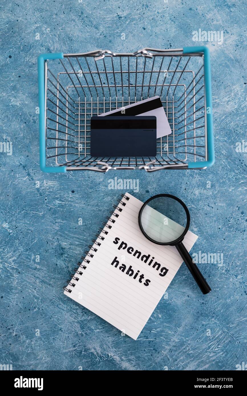 spending habits text on notepad with shopping basket and magnifying ...