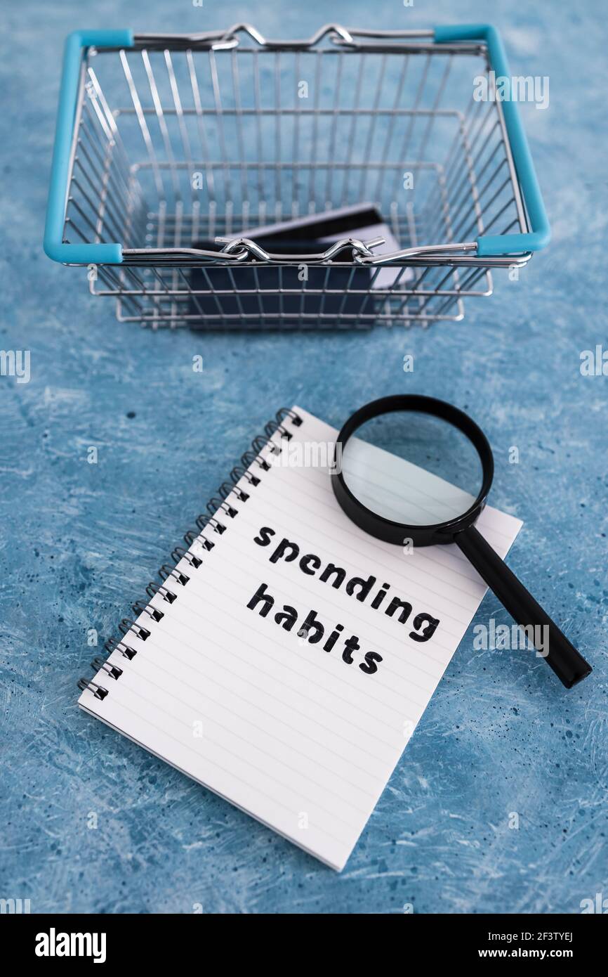 spending habits text on notepad with shopping basket and magnifying ...