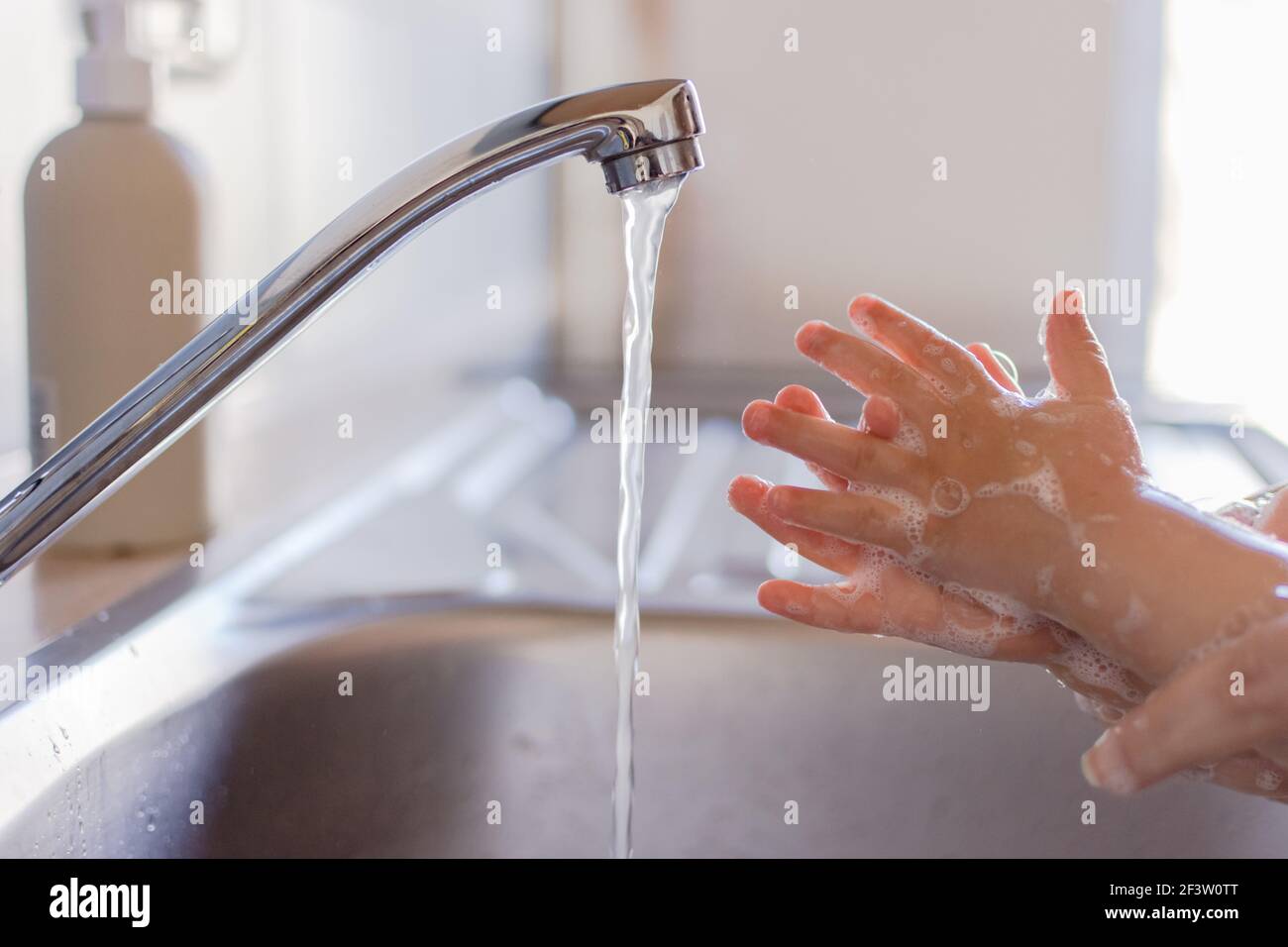 Close up hands of a small children washing hands with soap and water ...