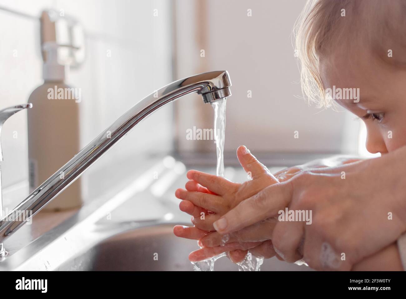 Close up hands of a small children washing hands with soap and water ...