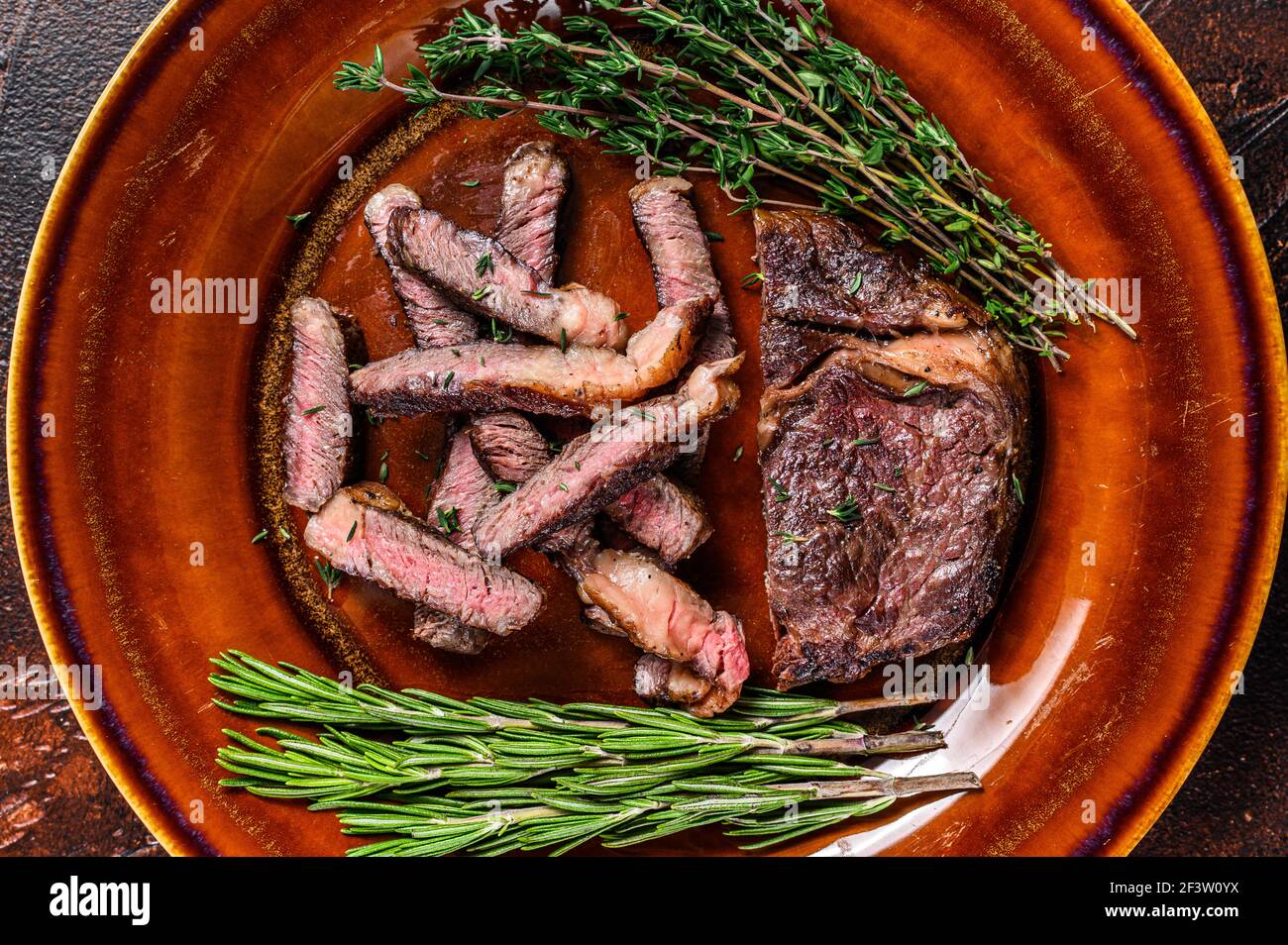 Grilled sliced rib eye or ribeye beef meat steak on a rustic plate ...