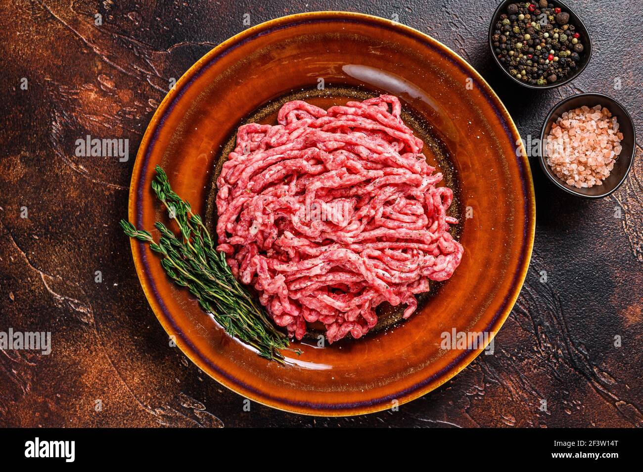 Raw mince angus wagyu beef, ground meat with herbs on a plate. Dark ...