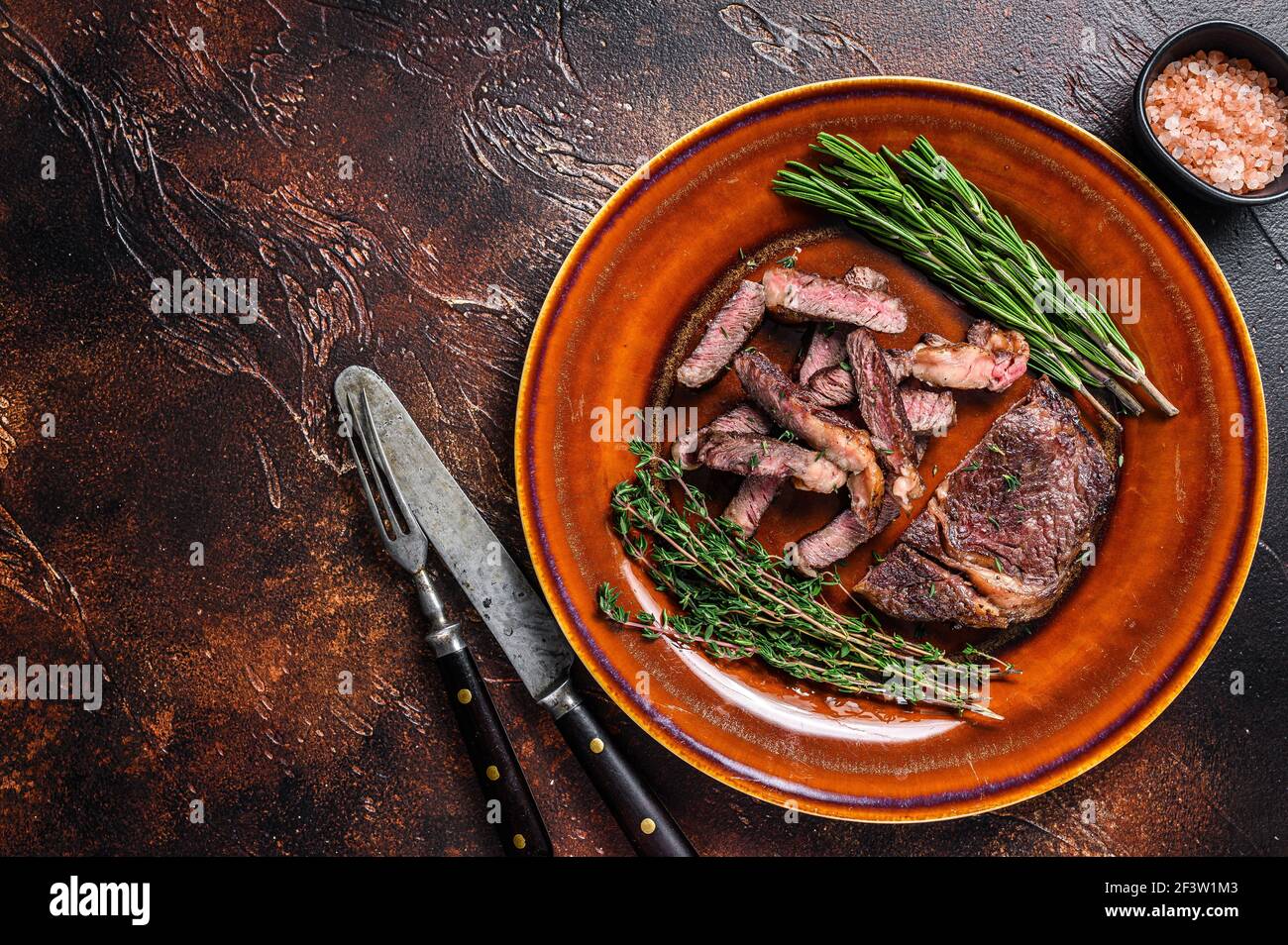 Grilled sliced rib eye or ribeye beef meat steak on a rustic plate ...