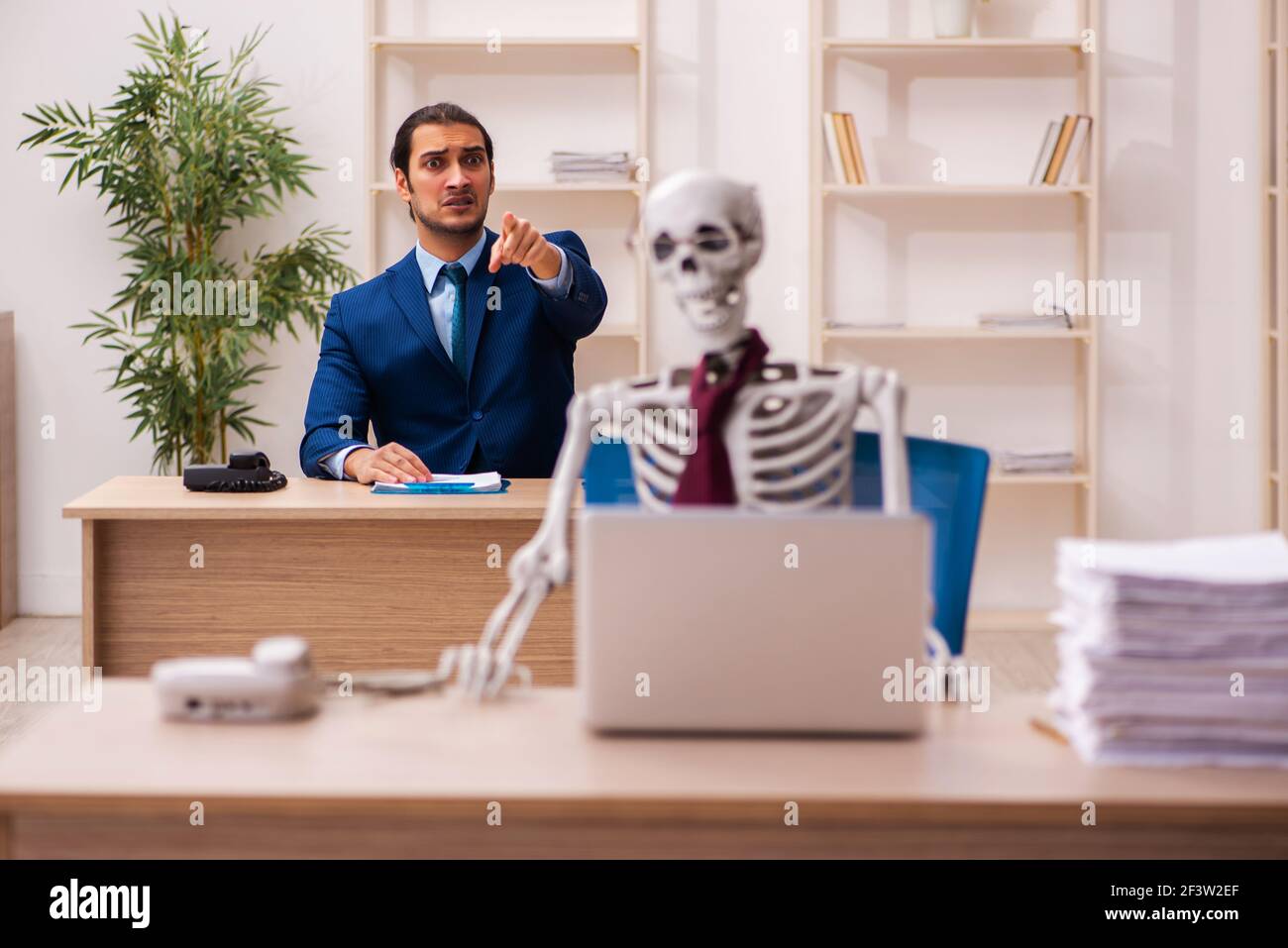 Dead employee working in the office in funny concept Stock Photo - Alamy