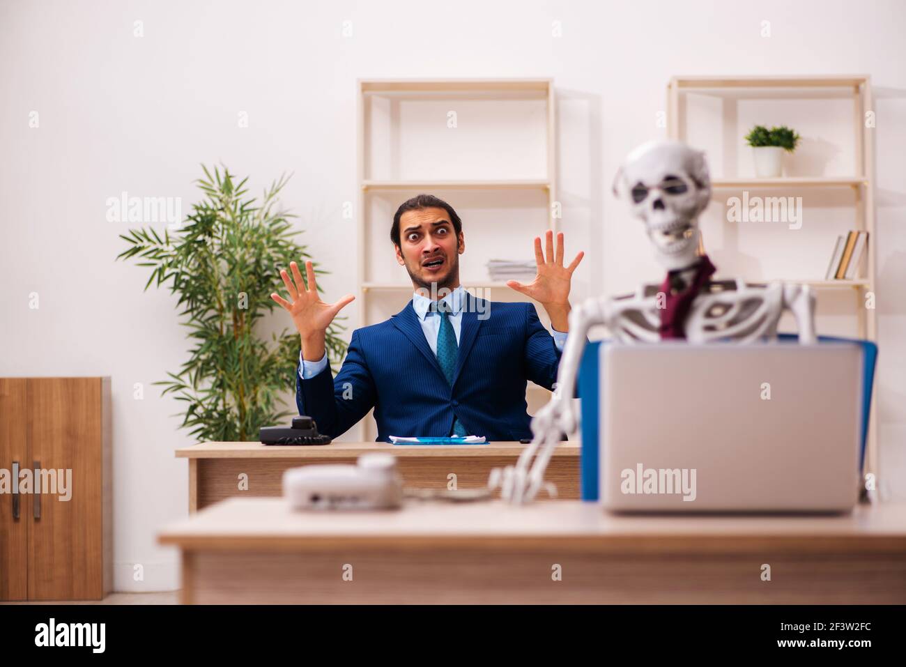 Dead employee working in the office in funny concept Stock Photo - Alamy