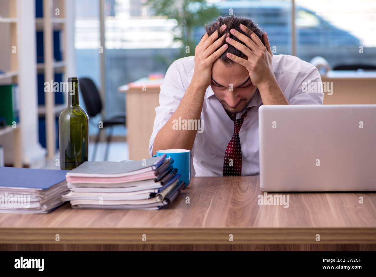 Young alcohol addicted employee working in the office Stock Photo - Alamy