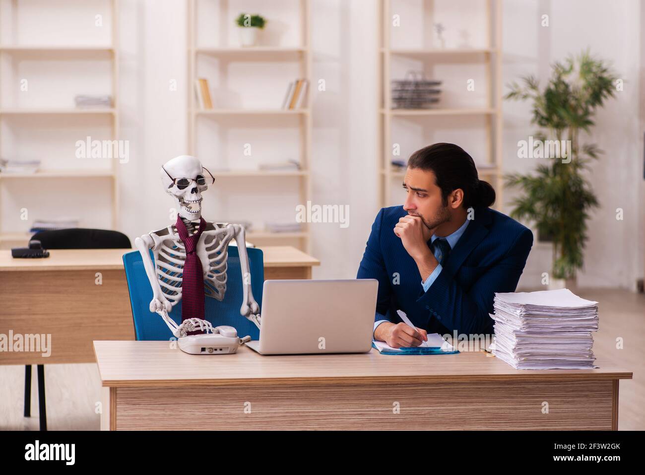 Dead employee working in the office in funny concept Stock Photo - Alamy